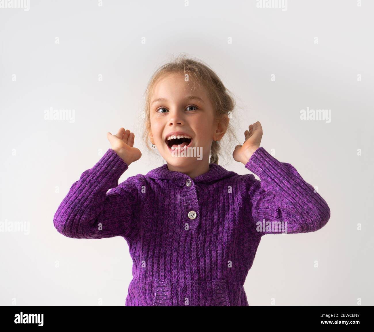 Amazed little girl flinging her arms up and crying in delight, getting ...