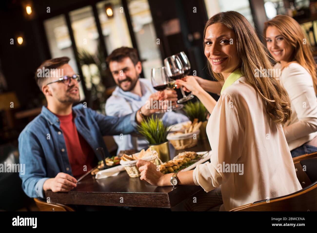 Group of happy young people having dinner in the restaurant Stock Photo ...