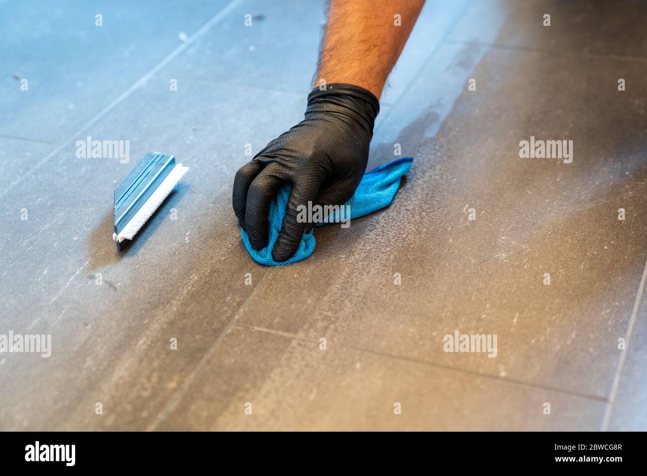 A close up of a professional cleaner cleaning grout with a blue cloth ...