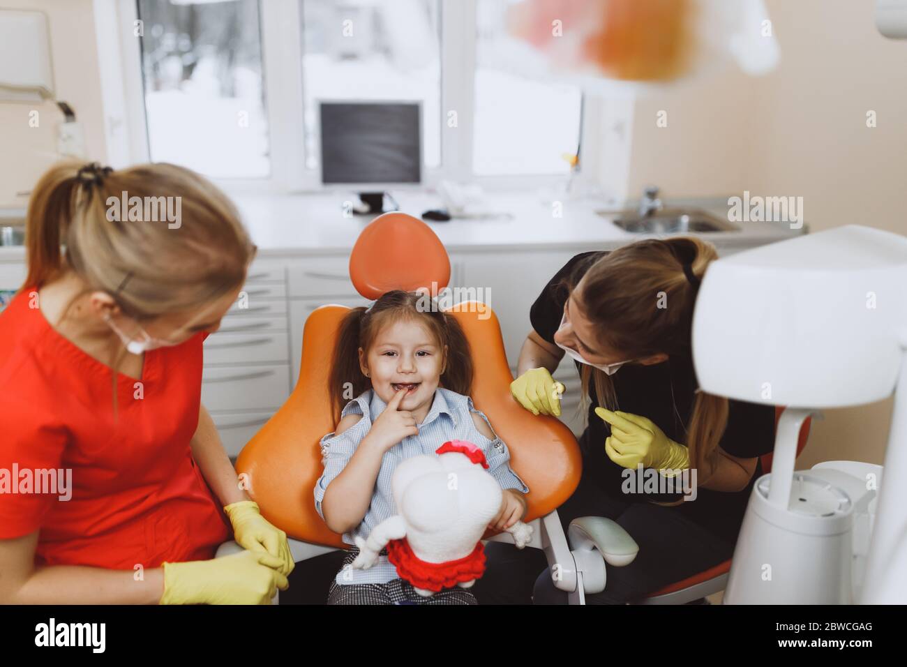 High angle of cheerful little patient smiling and pointing at teeth ...