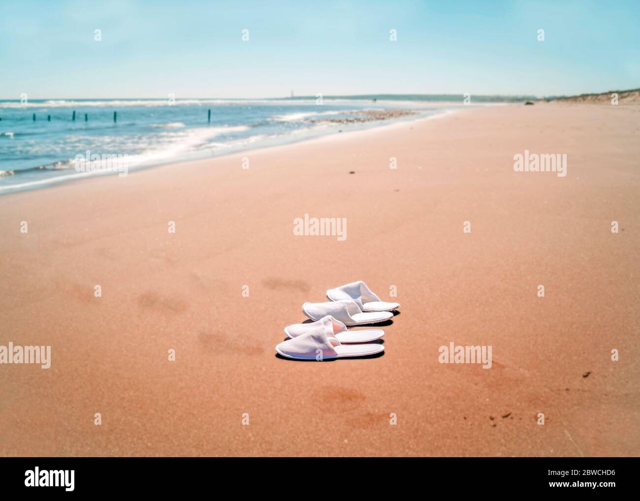 Sunny day, Two pairs of white hotel slippers side by side on sandy ...
