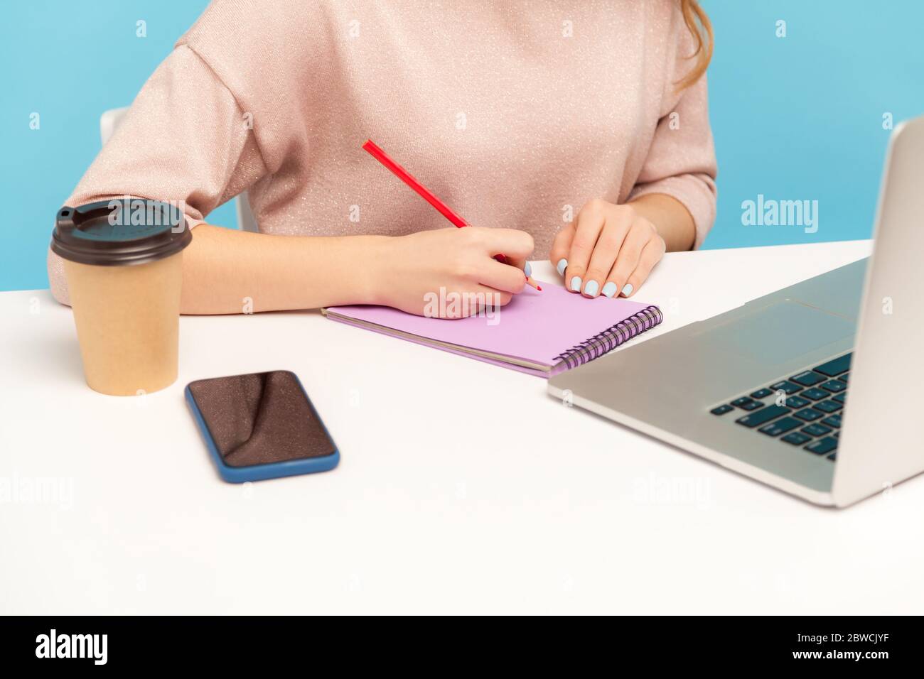 Closeup of female journalist making notes with pencil on paper notebook ...