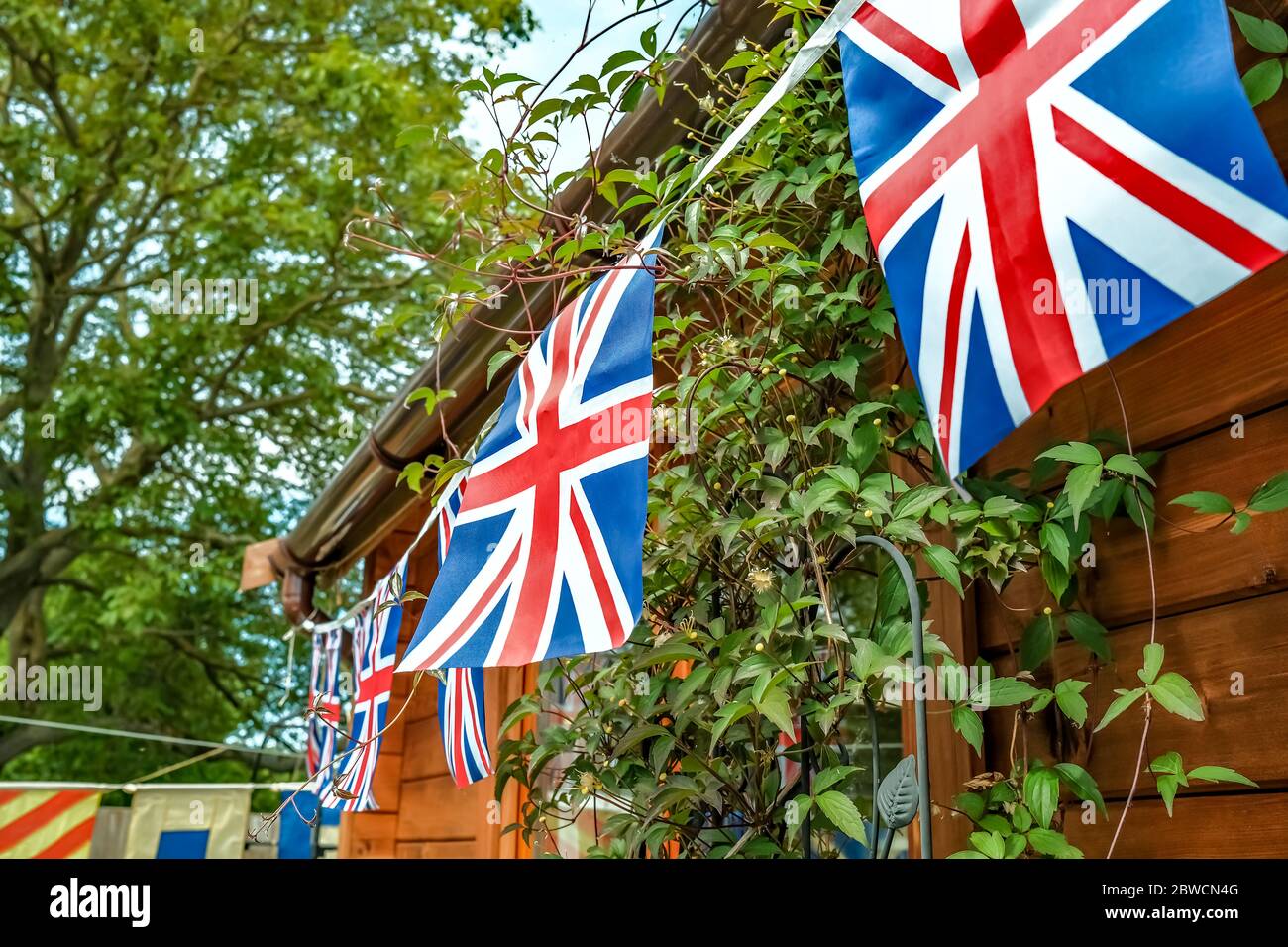 5 Union Jack bunting hanging on a wooden log cabin Stock Photo - Alamy