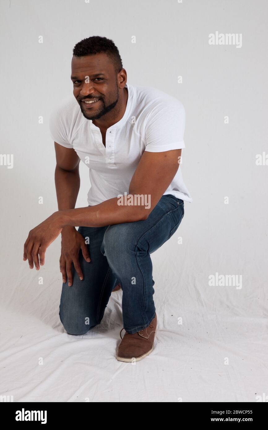 Happy Black Man Kneeling Stock Photo - Alamy