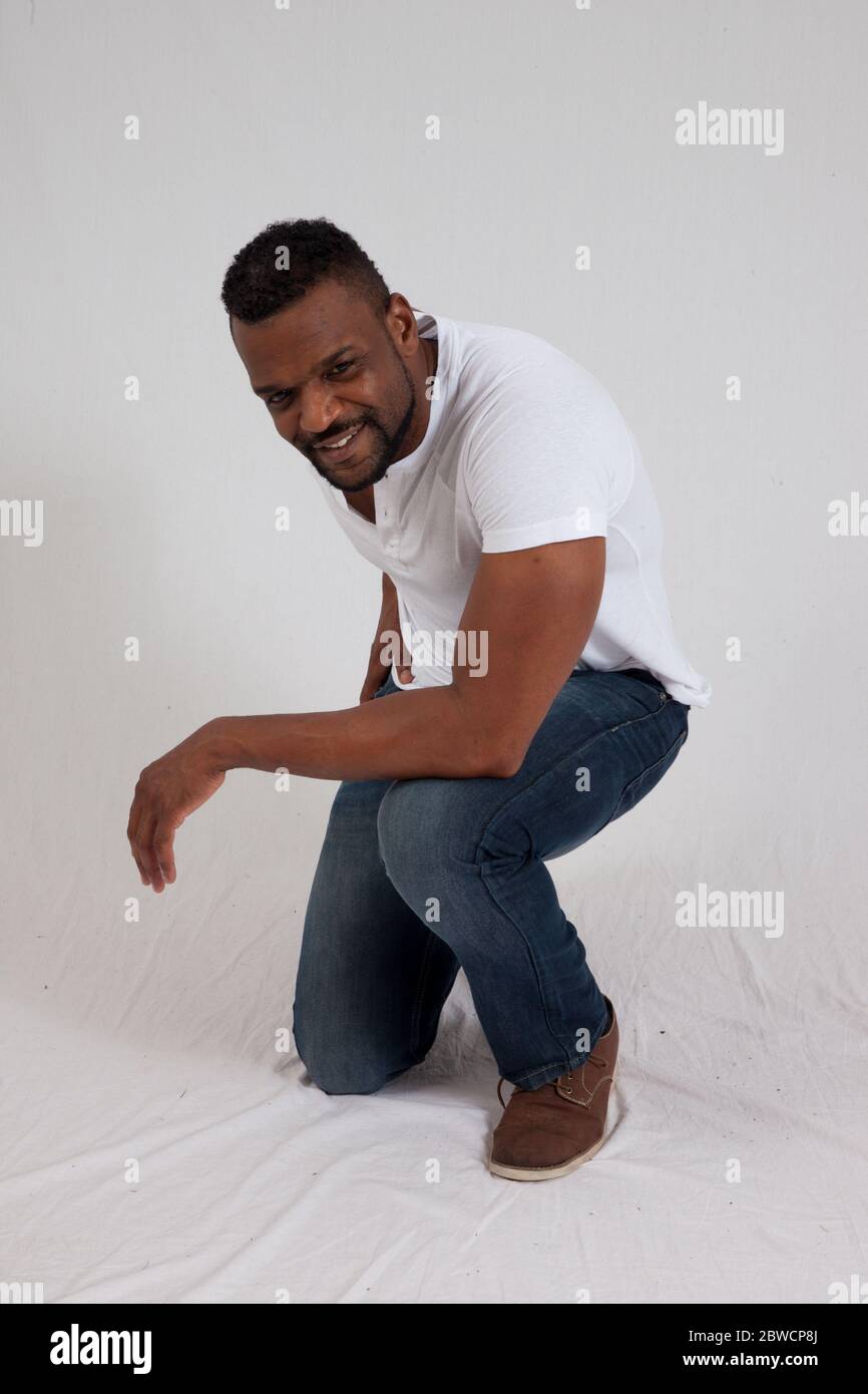 Happy Black Man Kneeling Stock Photo - Alamy