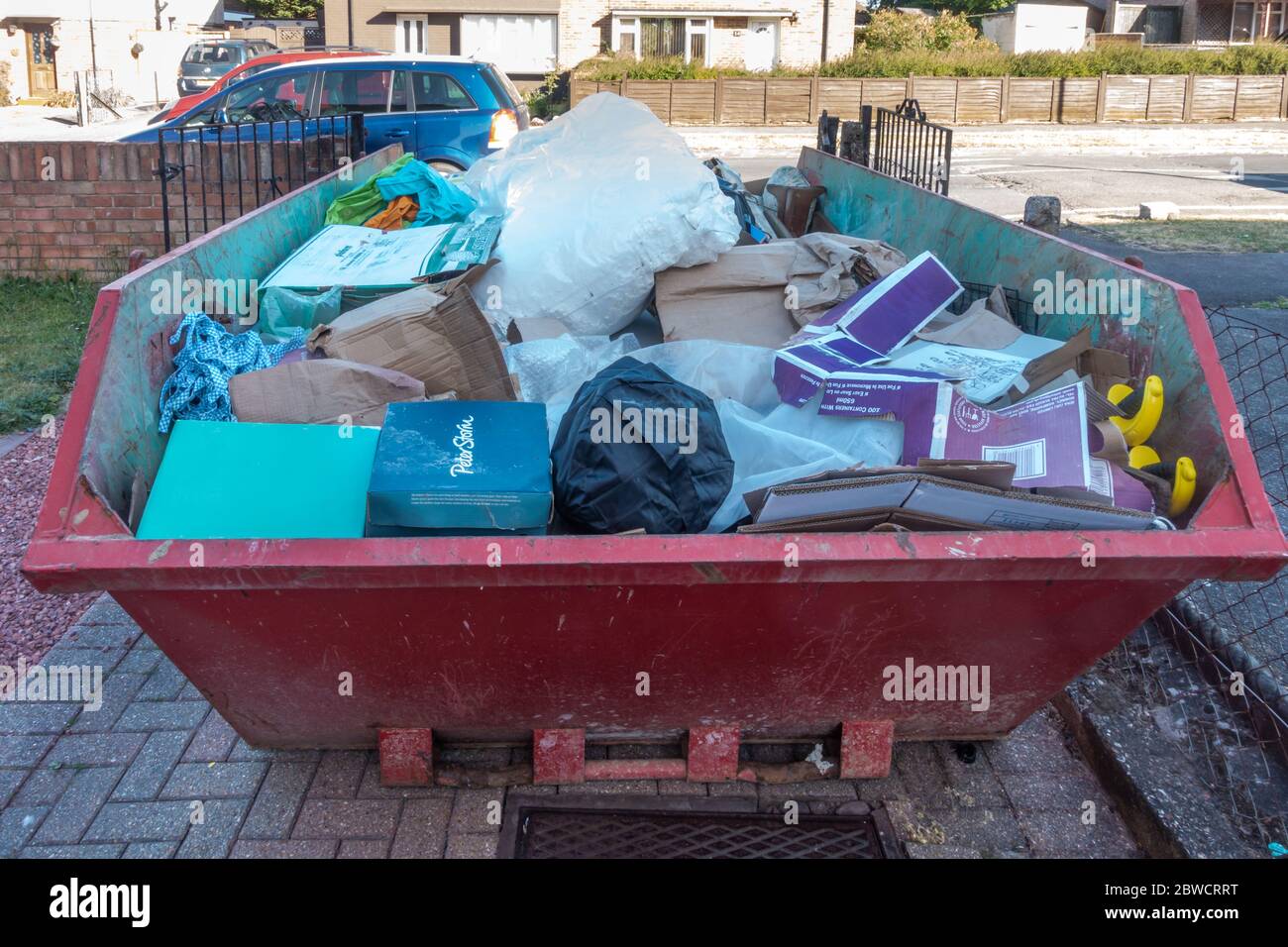A skip on the driveway of a residential house full of rubbish as the ...