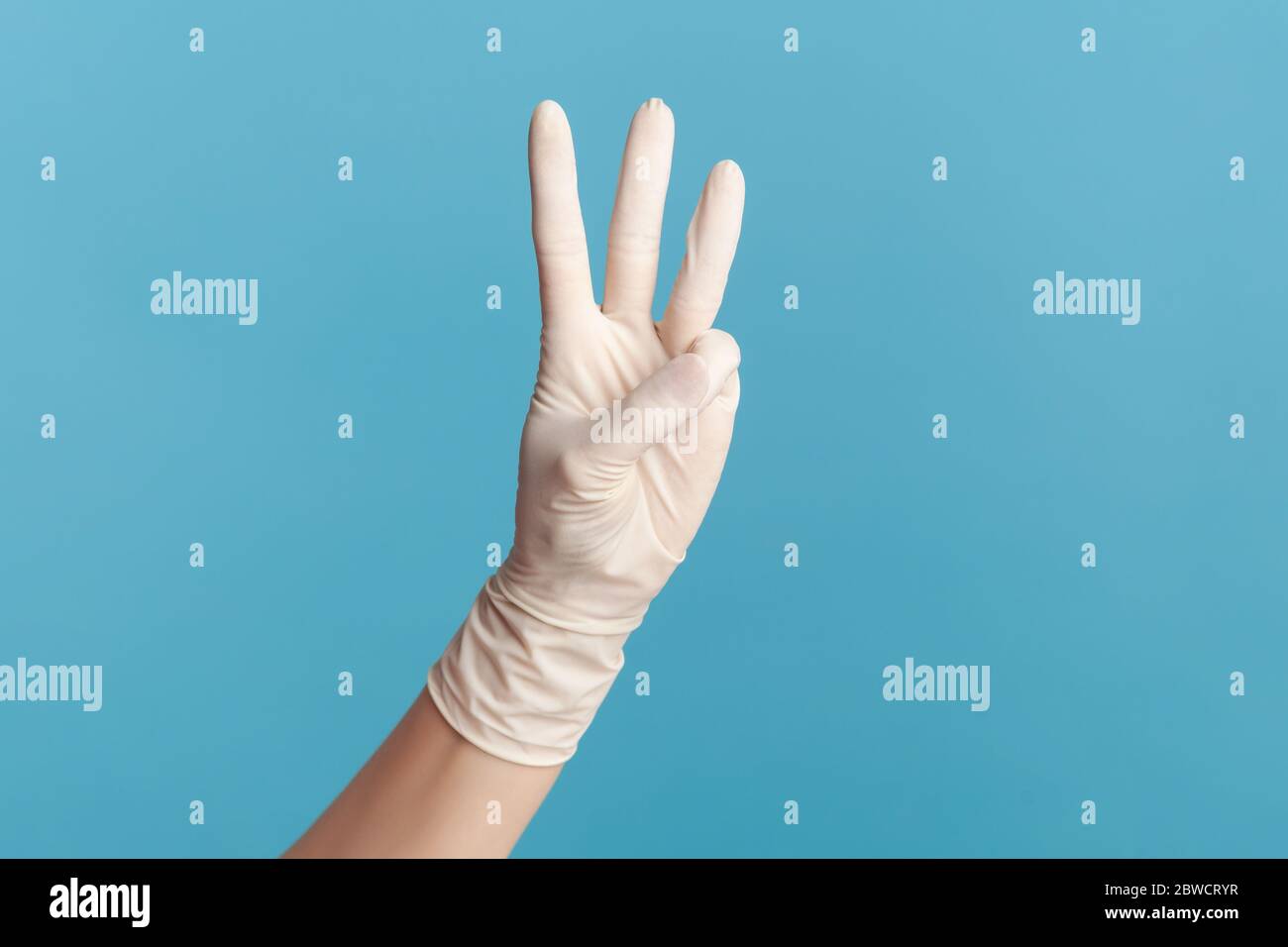 Profile side view closeup of human hand in white surgical gloves ...