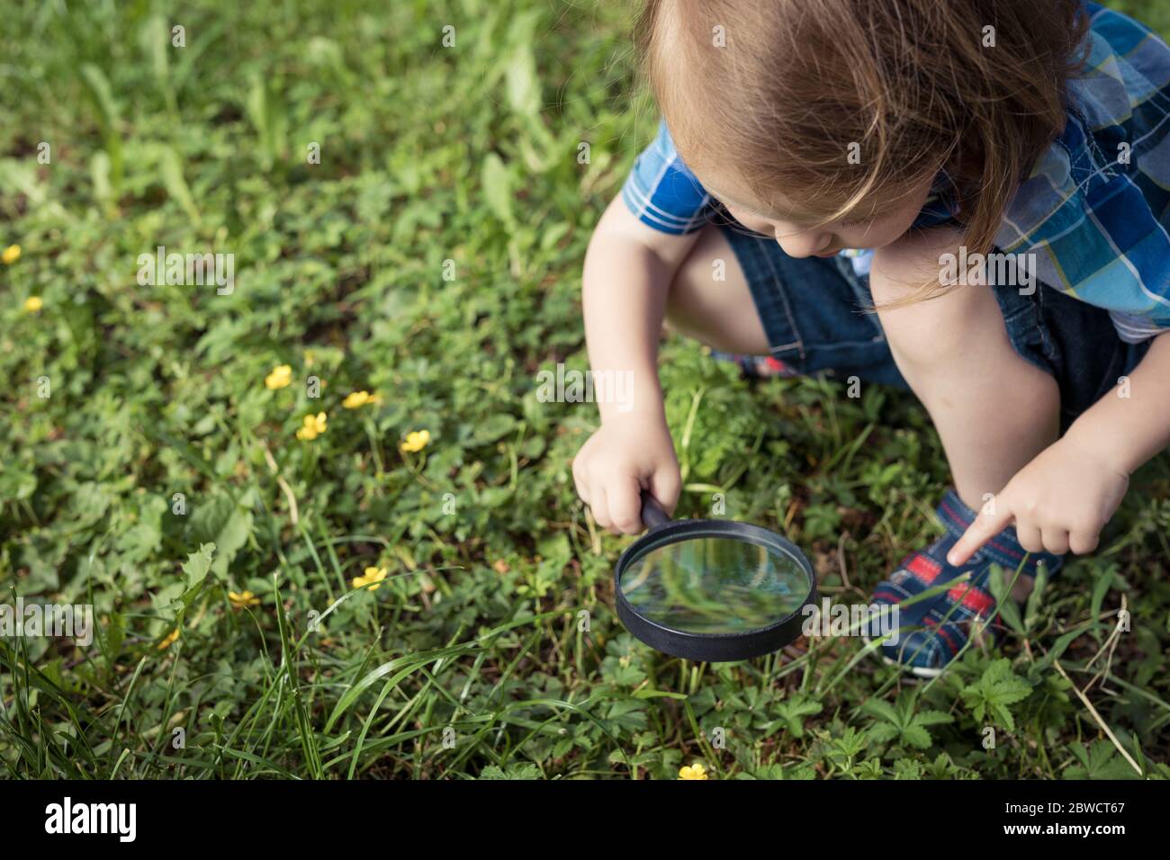 Happy little boy exploring nature with magnifying glass at the day time ...