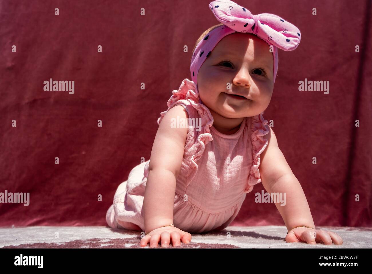 Cute baby girl wear adorable hat doing push-up outdoors, looking at ...