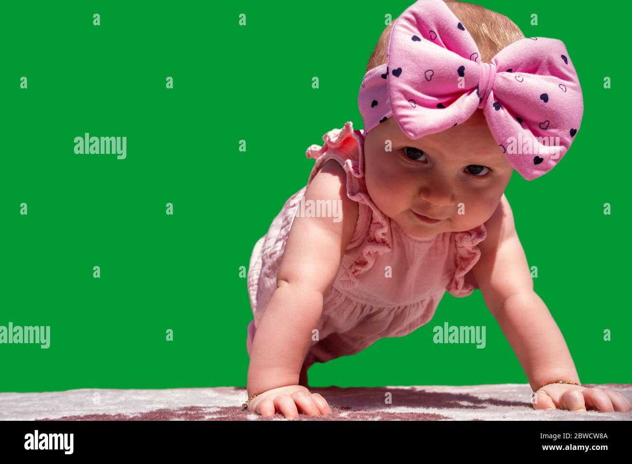 Cute baby girl wear adorable hat doing push-up outdoors, looking at ...