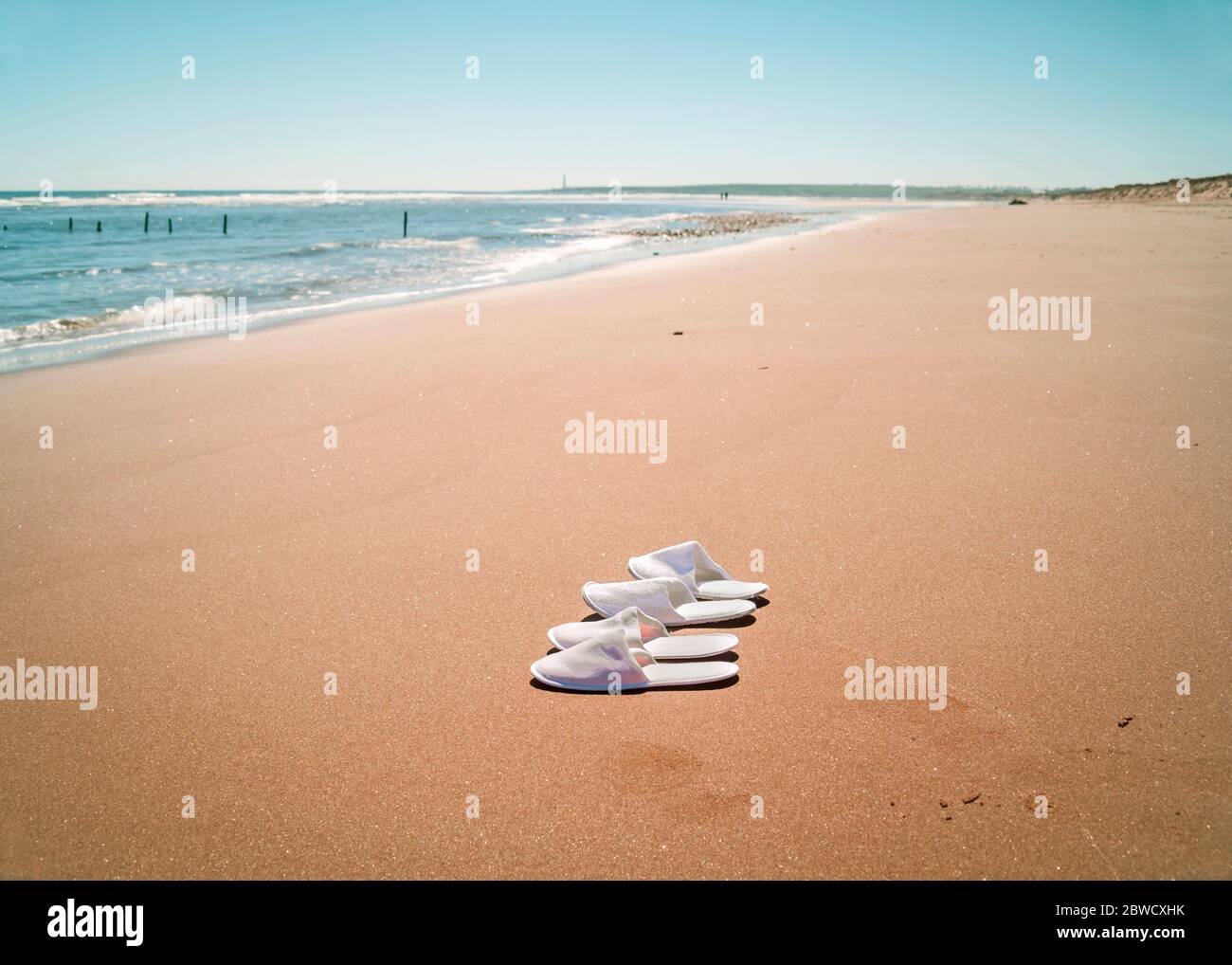 Sunny day, Two pairs of white hotel slippers side by side on sandy ...