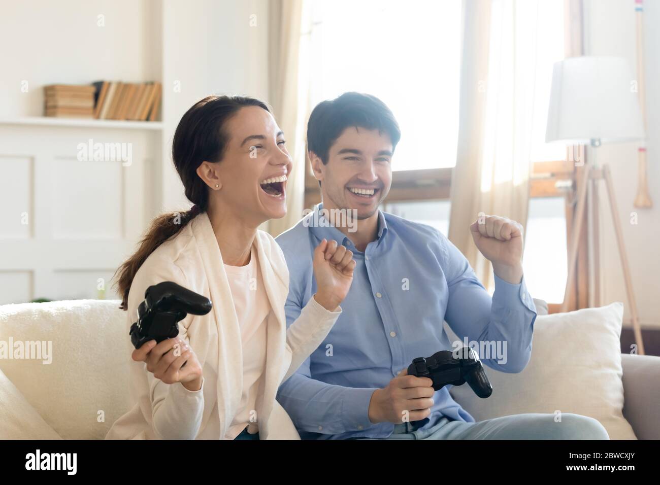 Overjoyed couple celebrate victory in video game Stock Photo - Alamy