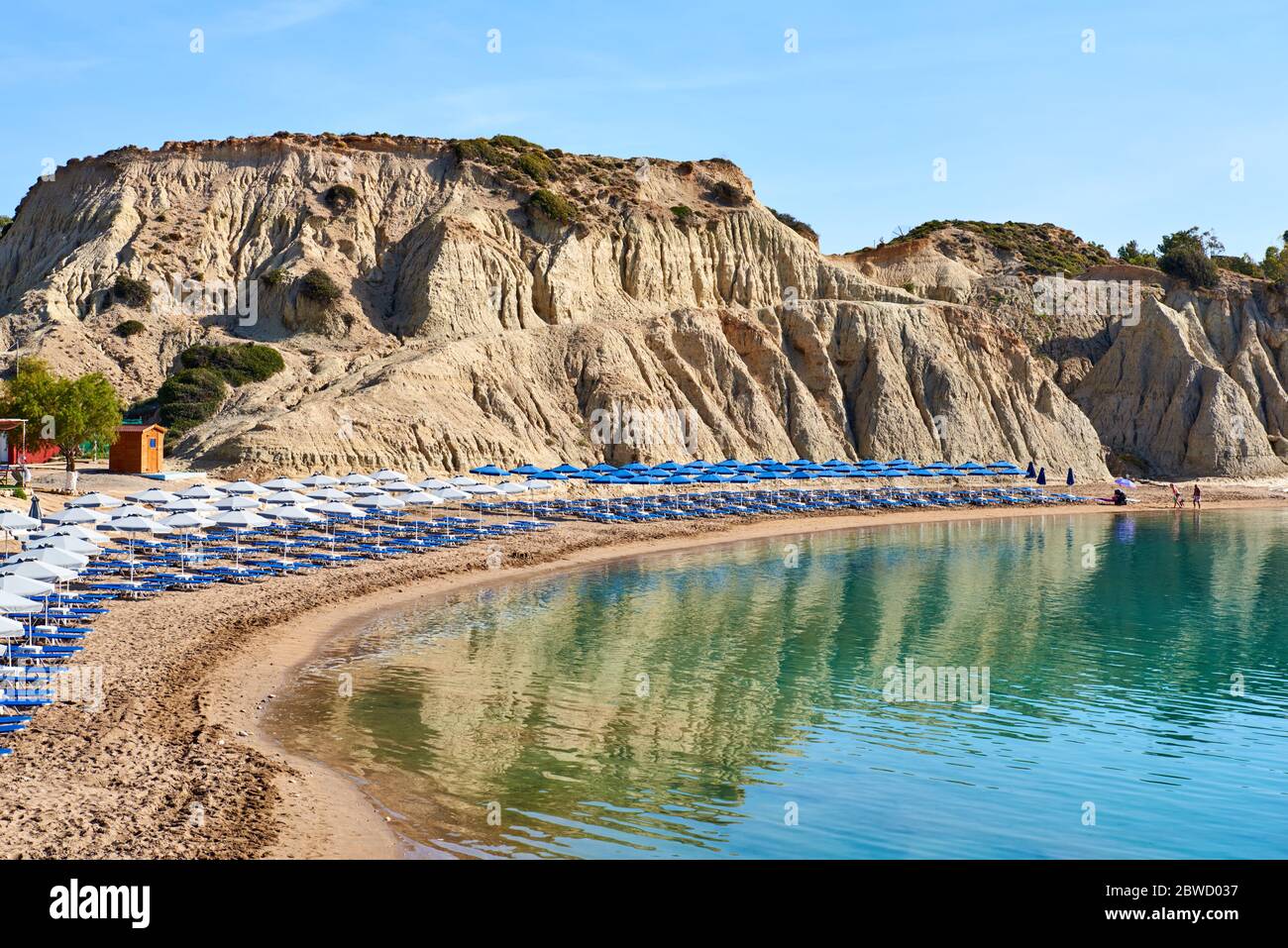 Sun loungers with umbrellas on beautiful Kolymbia beach with rocks in ...