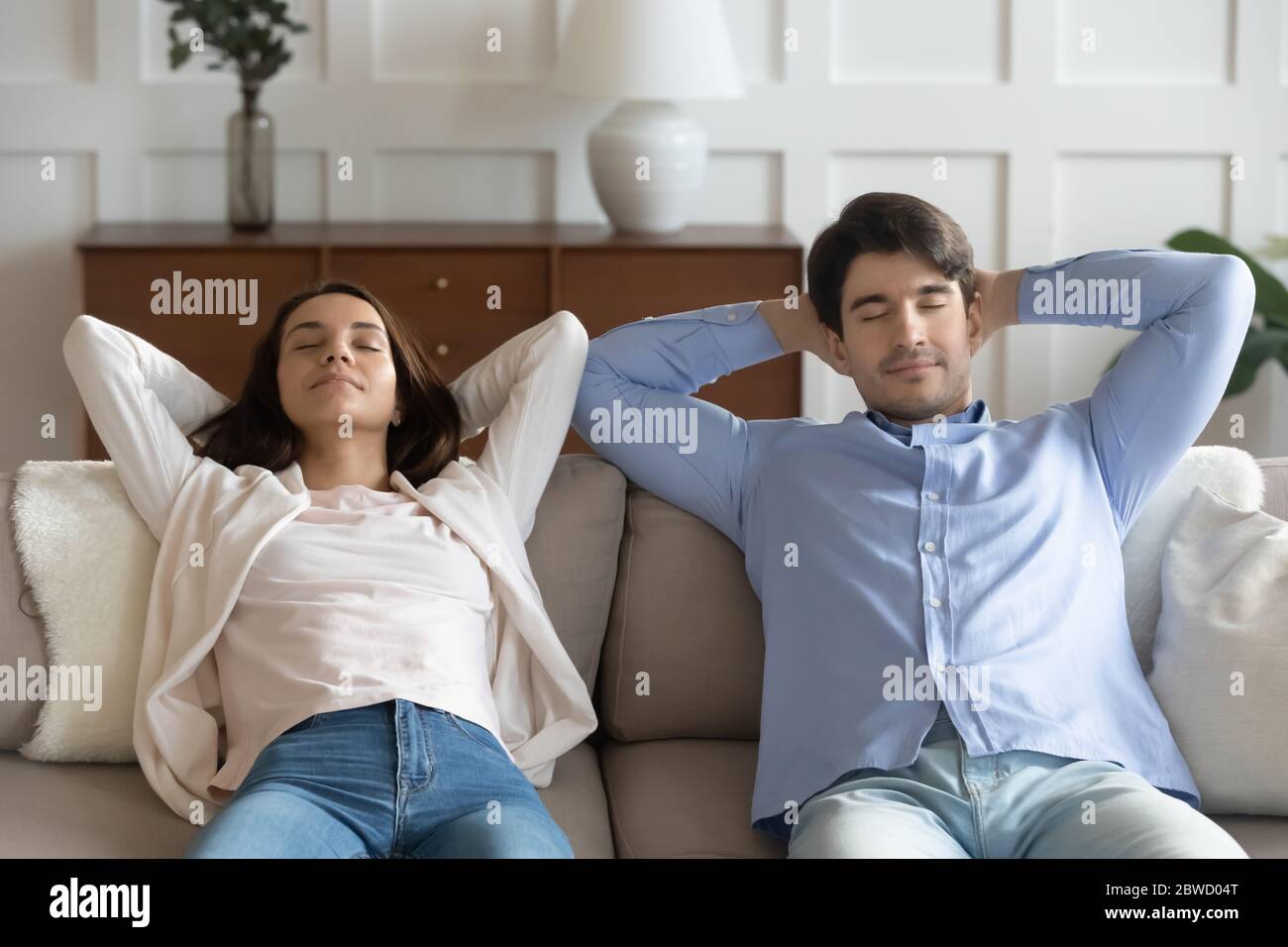 Millennial couple rest on sofa at home sleeping Stock Photo - Alamy