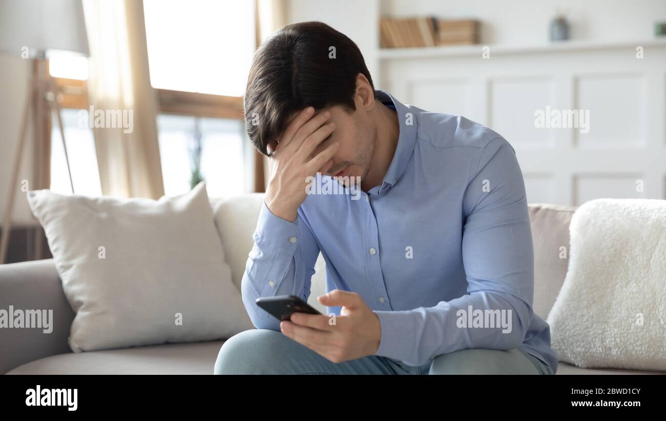 Upset man get unpleasant message on smartphone Stock Photo - Alamy