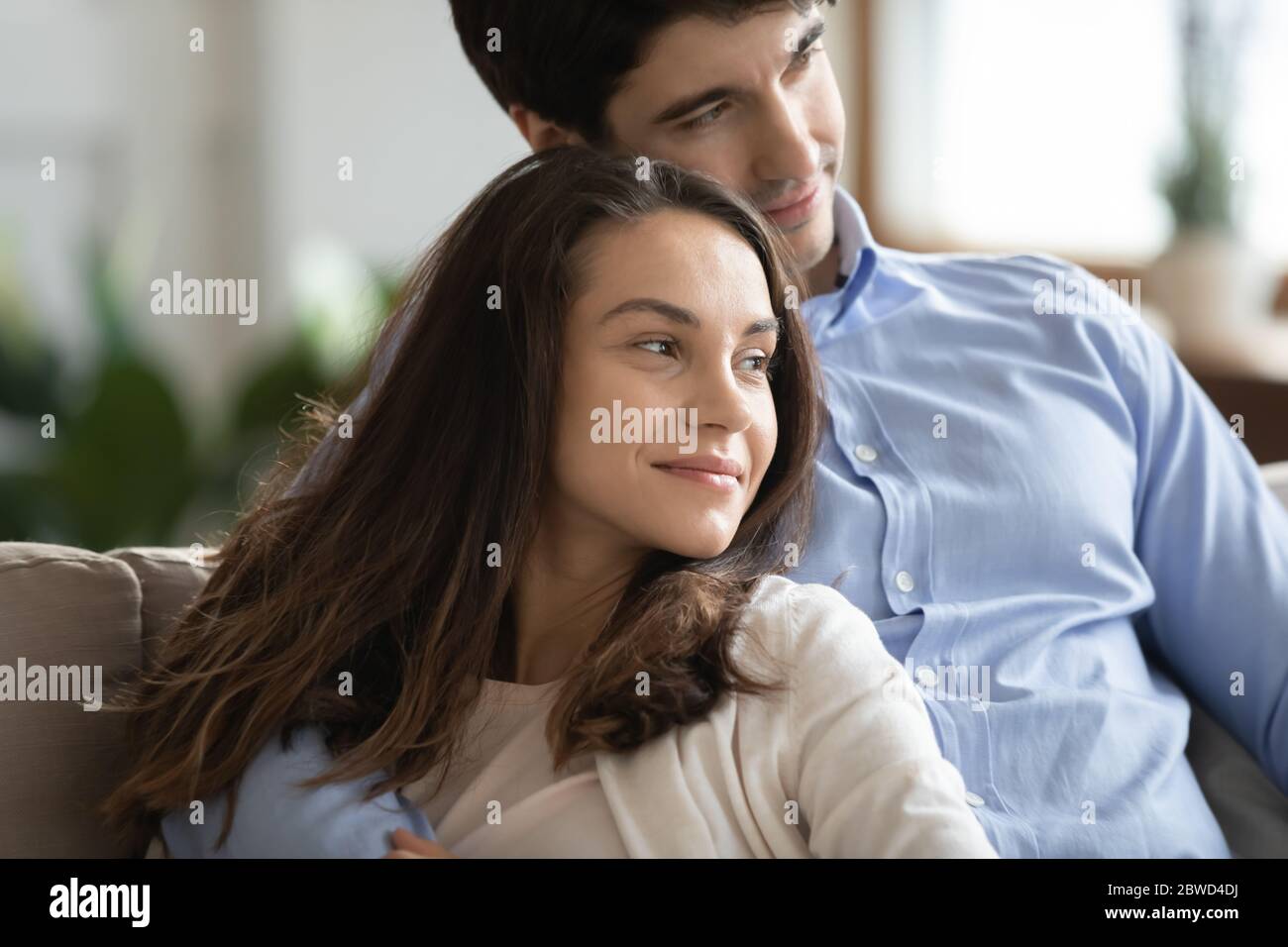 Happy young couple cuddle look in distance dreaming Stock Photo - Alamy