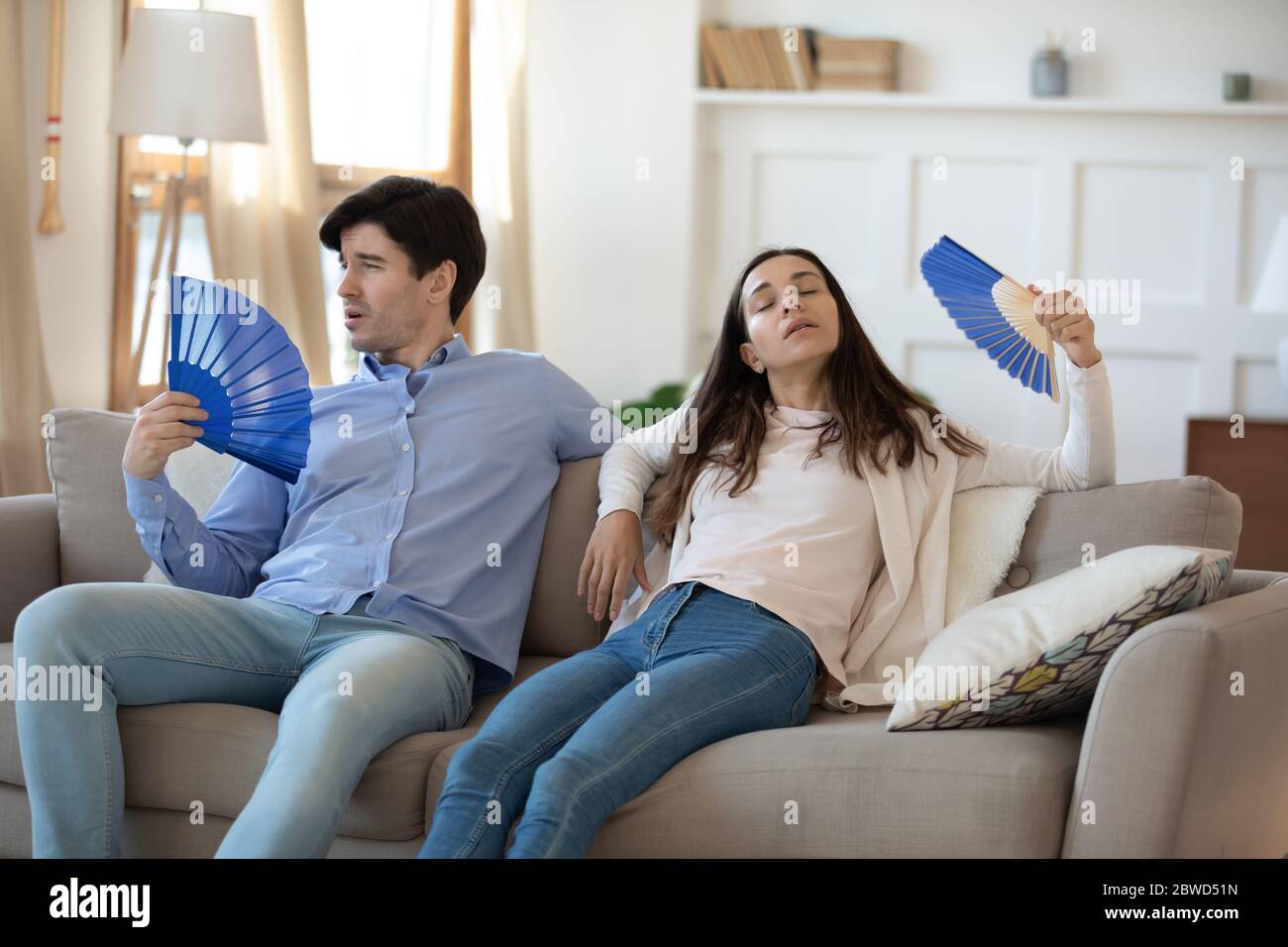 Unwell couple use hand fan suffering from hot weather Stock Photo - Alamy