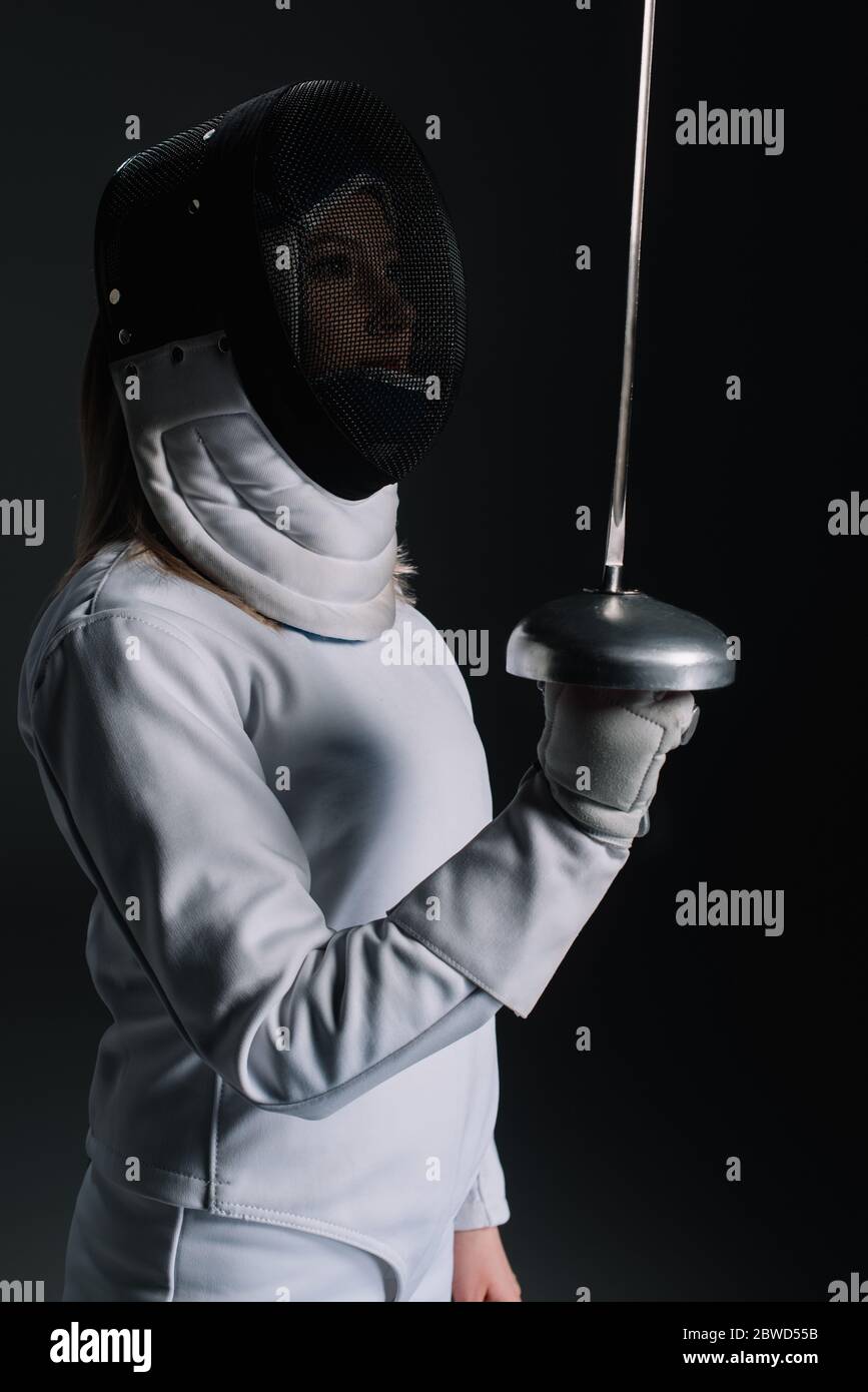 Side view of fencer in fencing mask holing rapier isolated on black ...