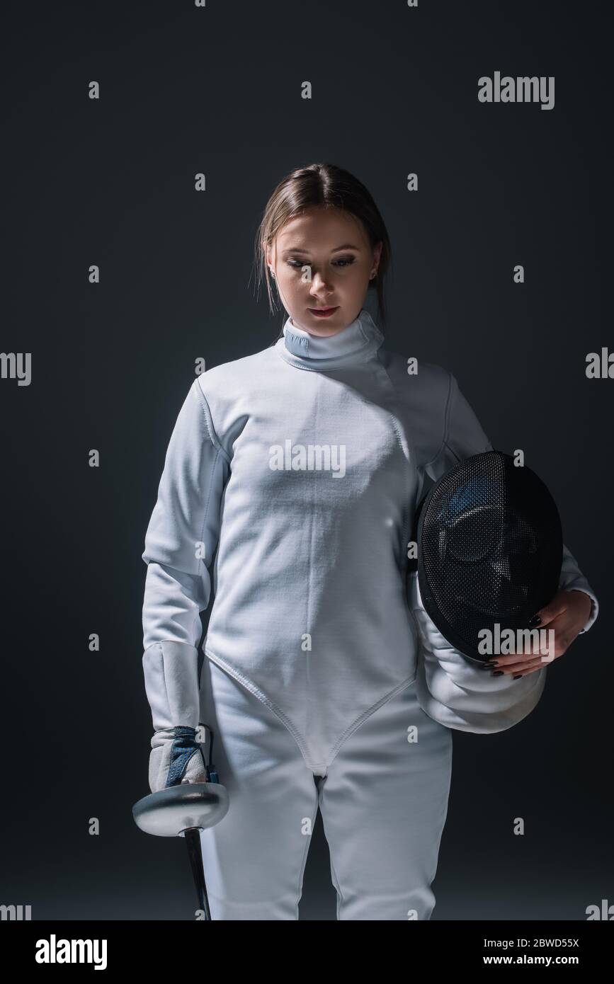Beautiful woman holding rapier and fencing mask isolated on black Stock ...
