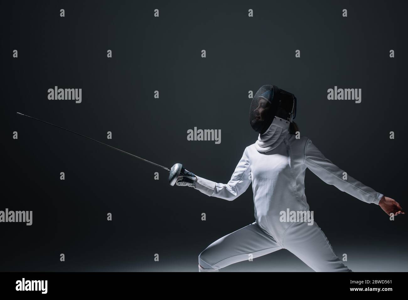 Fencer in fencing mask exercising on black background Stock Photo - Alamy