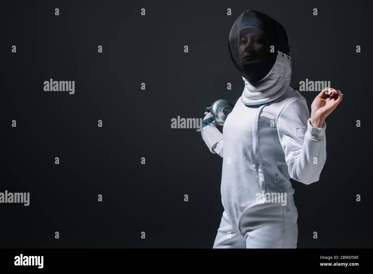 Fencer in fencing mask looking at camera while holding rapier isolated ...