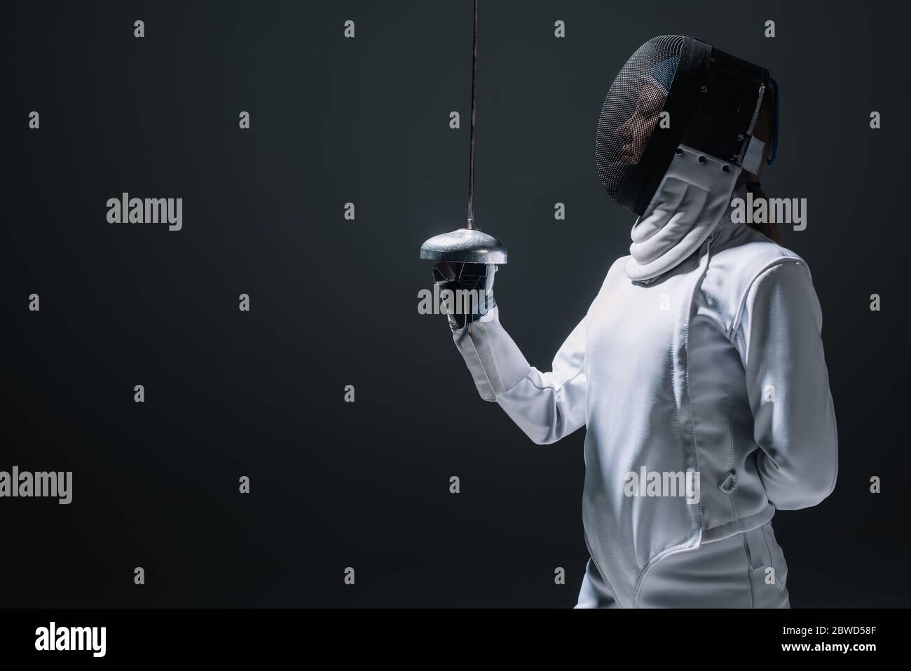 Side view of fencer in fencing mask holding rapier isolated on black ...