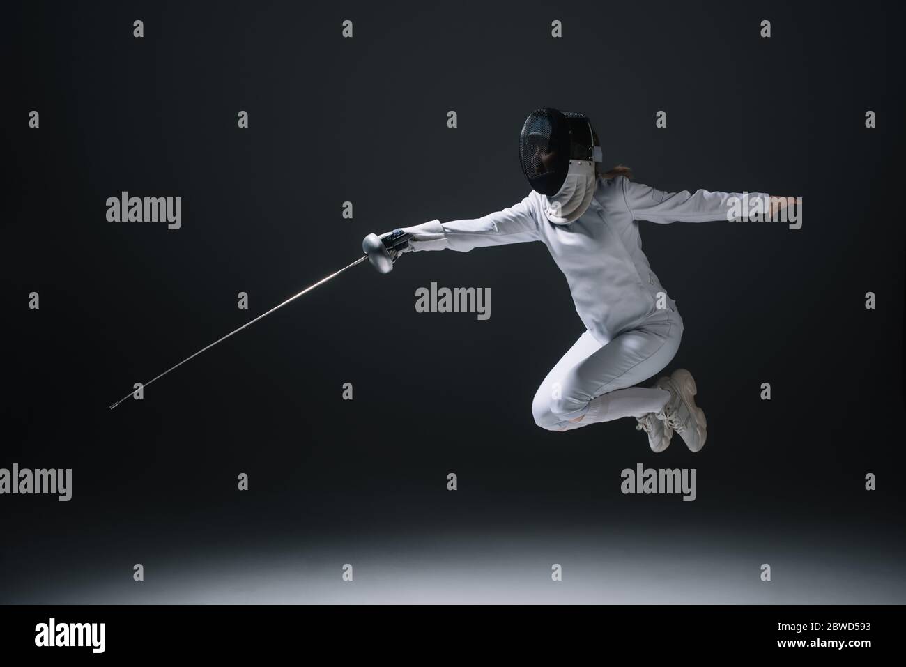 Fencer holding rapier while jumping isolated on black Stock Photo - Alamy