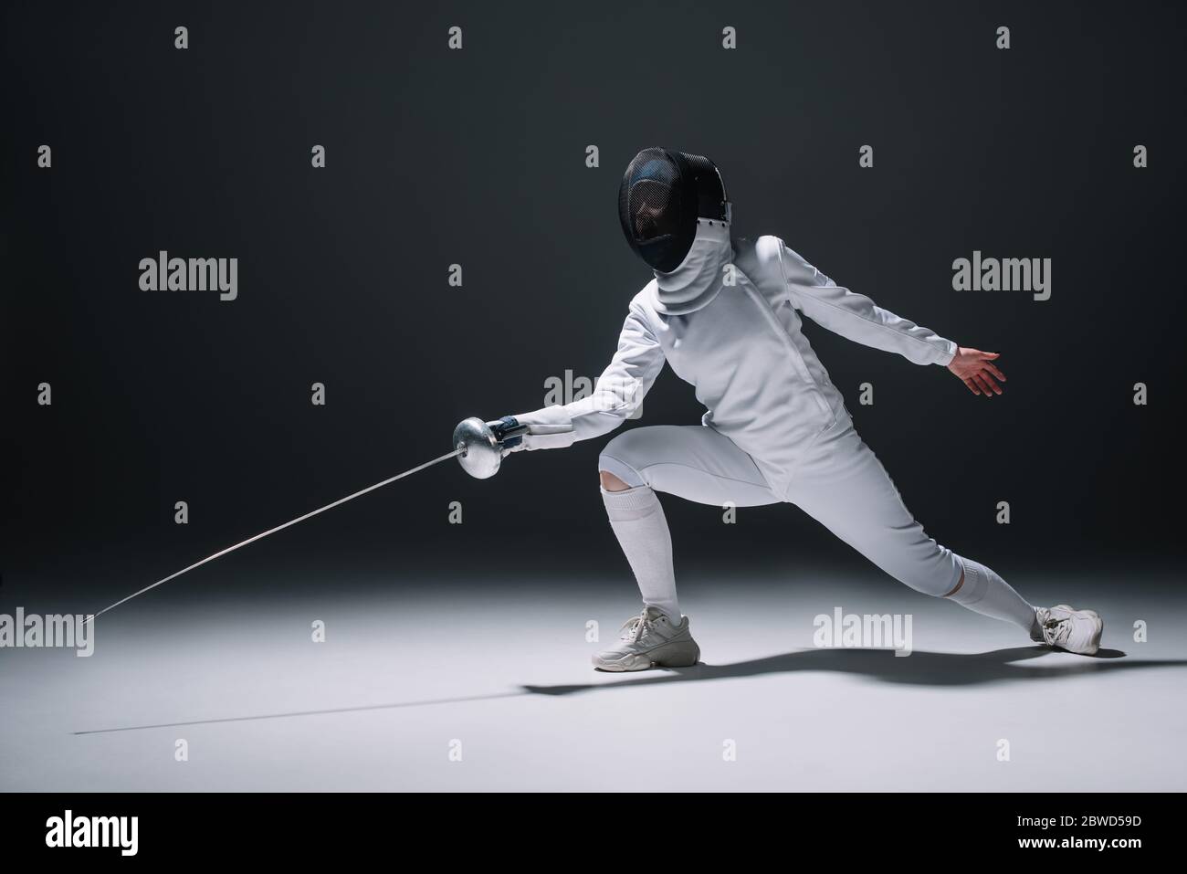 Fencer training under spotlight on black background Stock Photo - Alamy