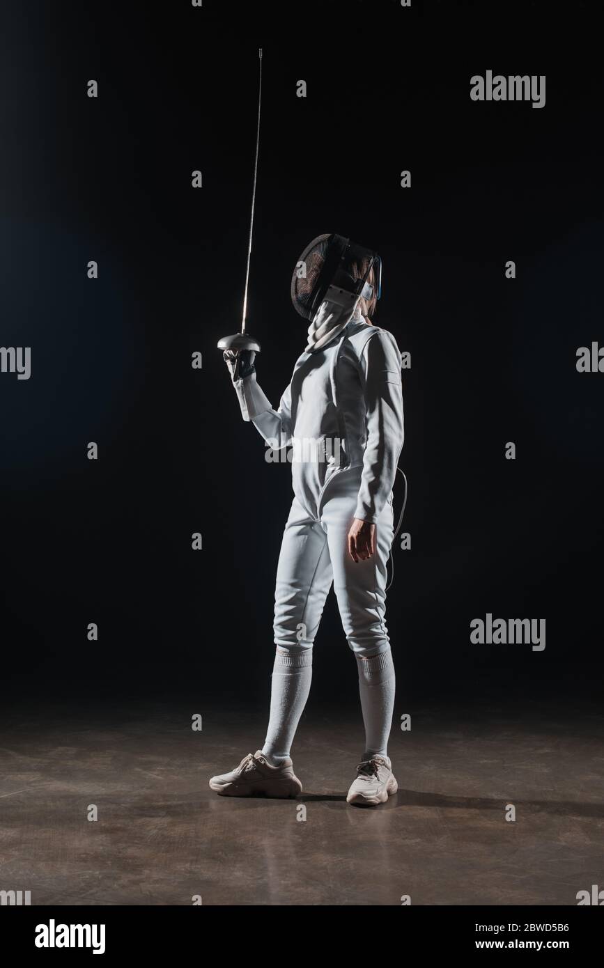 Fencer in fencing mask holding rapier on black background Stock Photo ...
