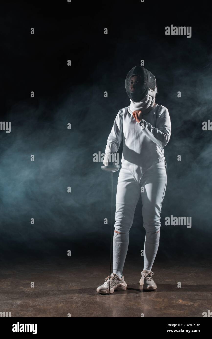 Fencer adjusting fencing mask on black background with smoke Stock ...