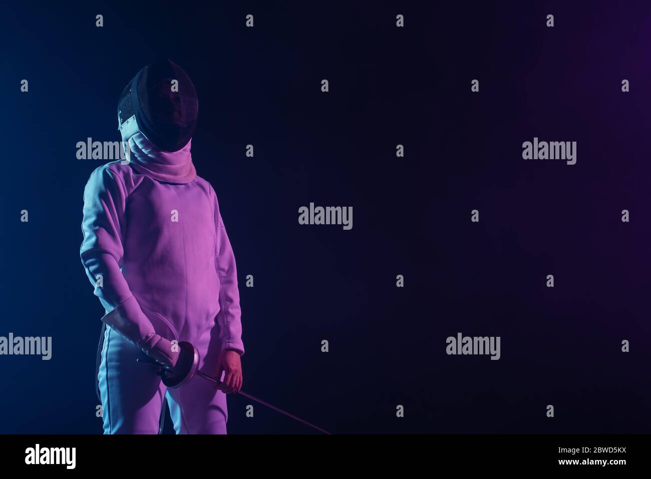 Fencer in fencing mask and suit holding rapier isolated on black Stock ...