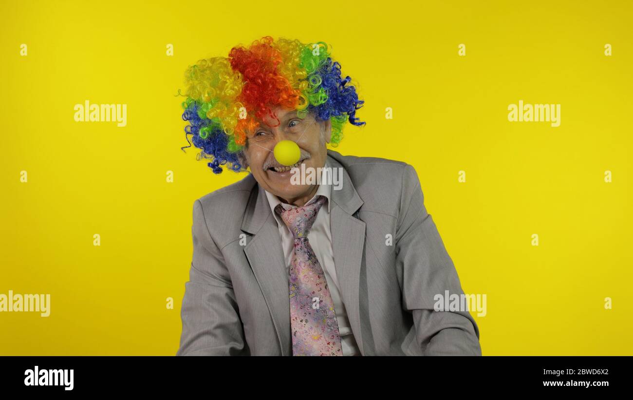 Senior clown manager office worker in wig and business suit at work ...