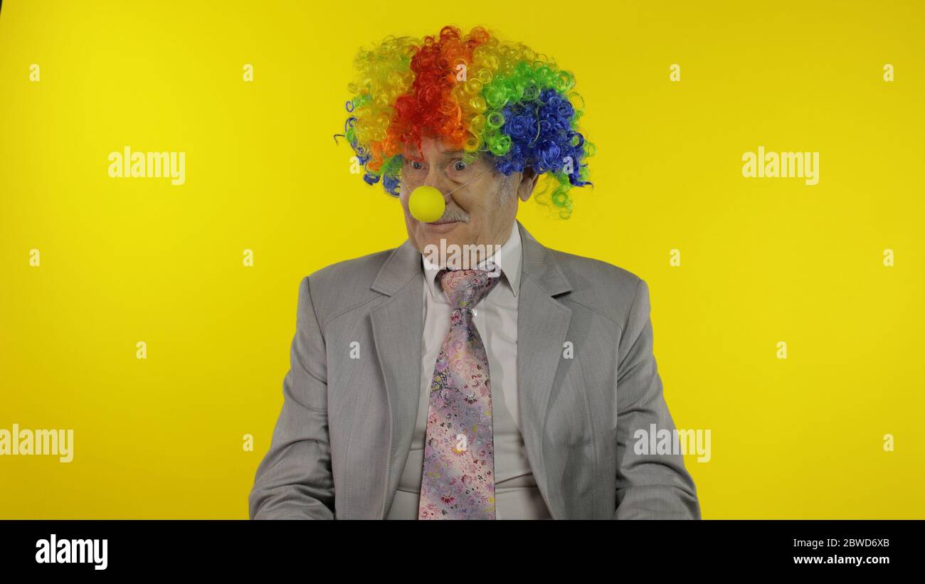 Senior clown manager office worker in wig and business suit at work ...