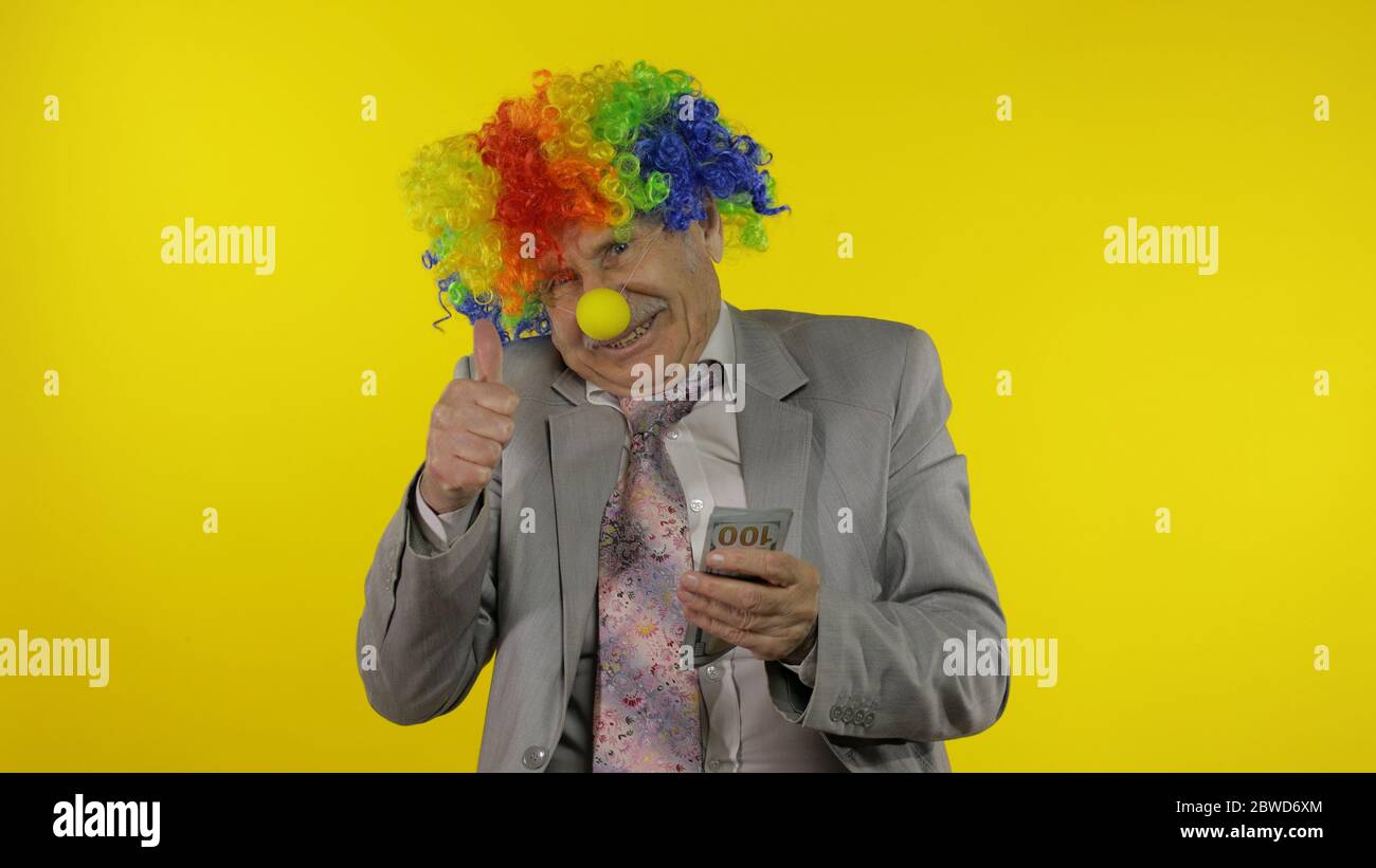 Senior clown director office worker in wig and business suit at work ...