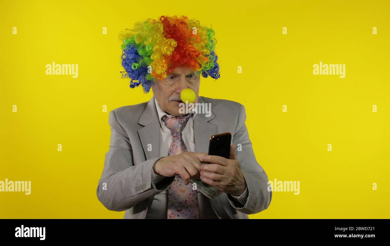 Senior clown director office worker in wig and business suit receives ...