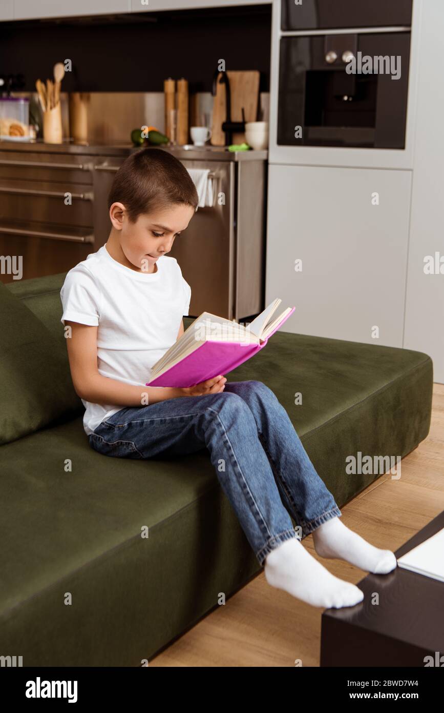 Selective focus of child reading book on couch at home Stock Photo - Alamy