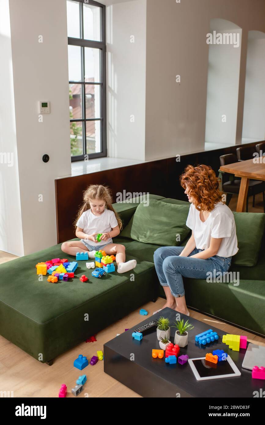 redhead mother looking at daughter playing building blocks Stock Photo - Alamy