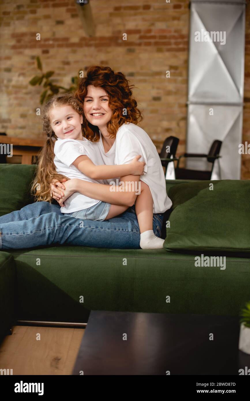 cute daughter hugging cheerful and curly mother Stock Photo - Alamy