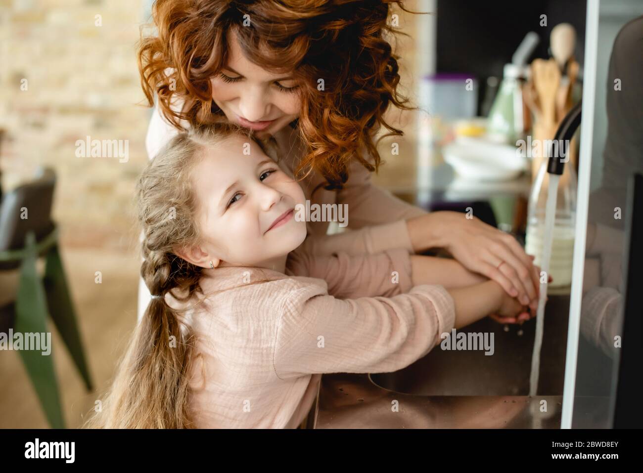 curly mother near happy daughter washing hands Stock Photo - Alamy