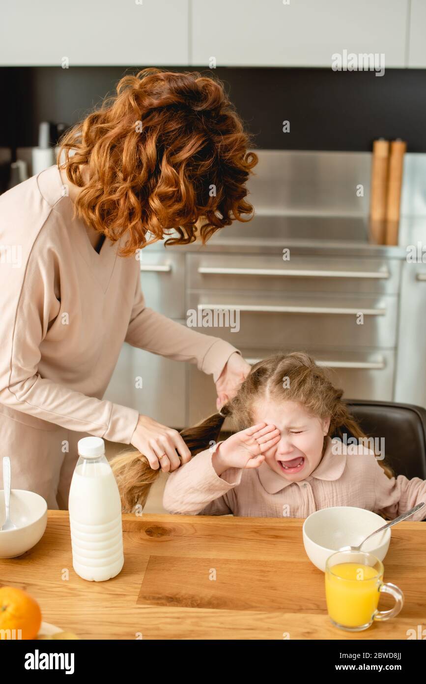 curly mother near upset daughter crying near breakfast Stock Photo - Alamy