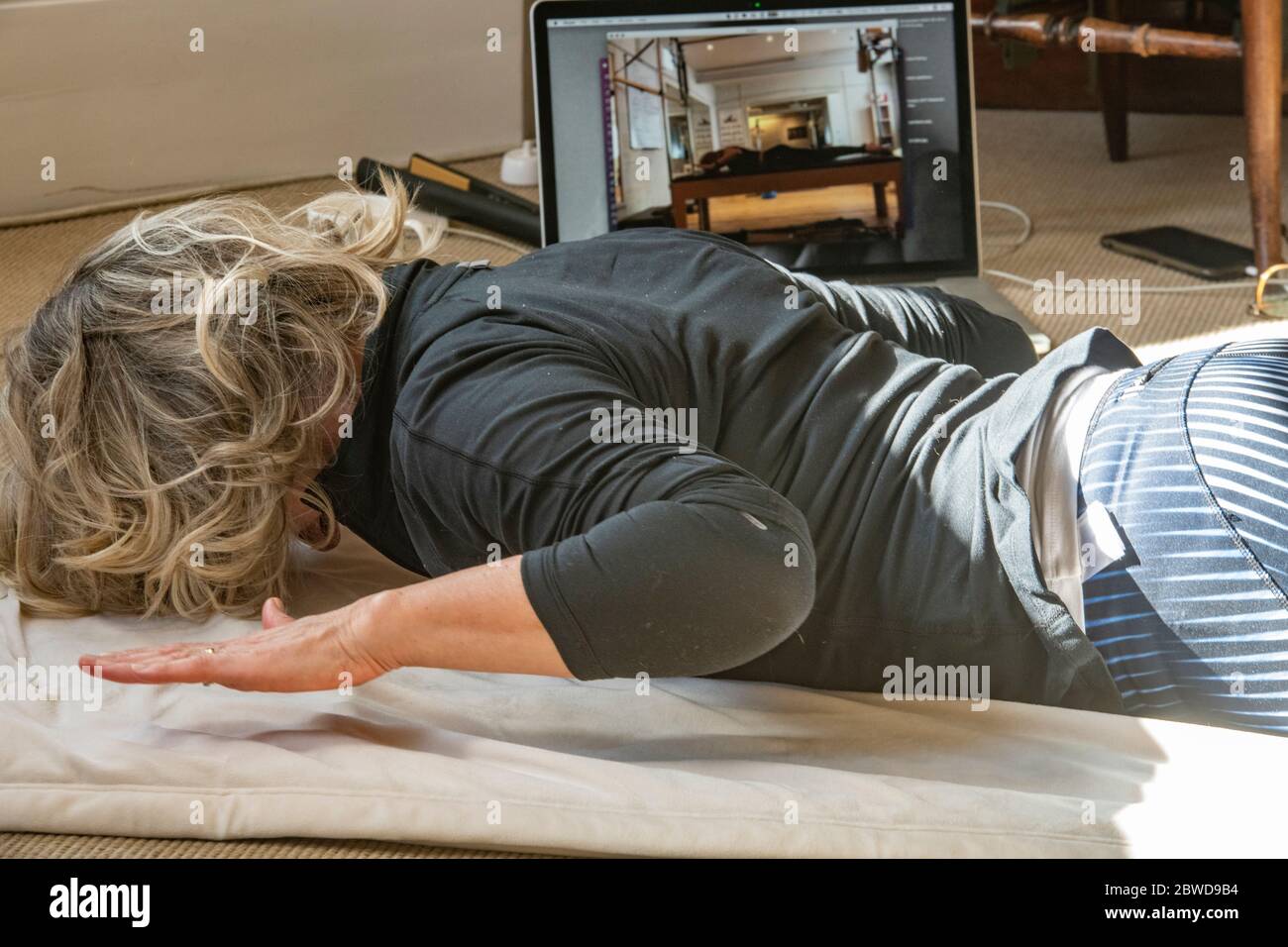 A woman has a pilates lesson over Zoom at home during the Coronavirus ...