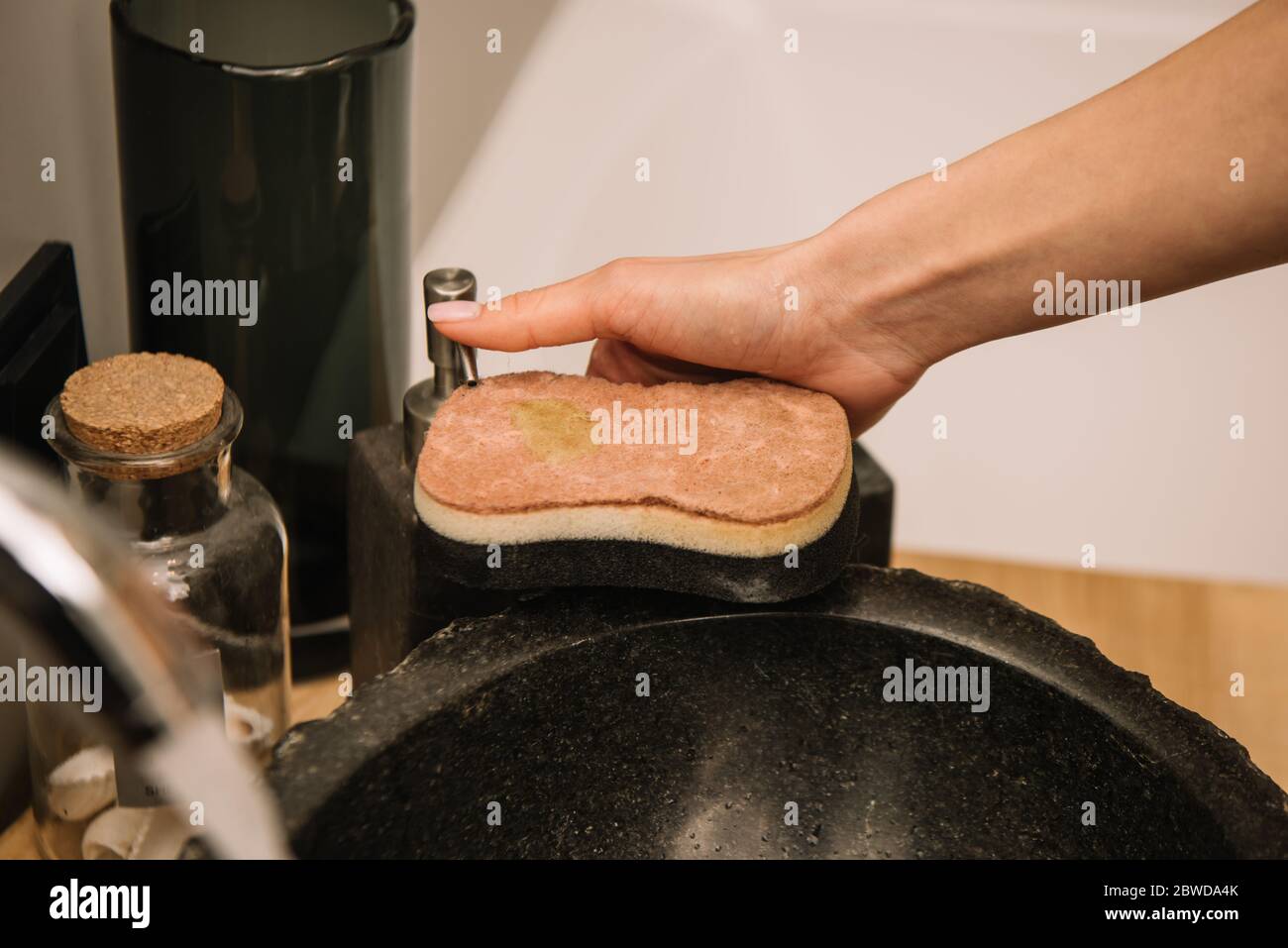 partial view of woman holding sponge near black sink Stock Photo - Alamy