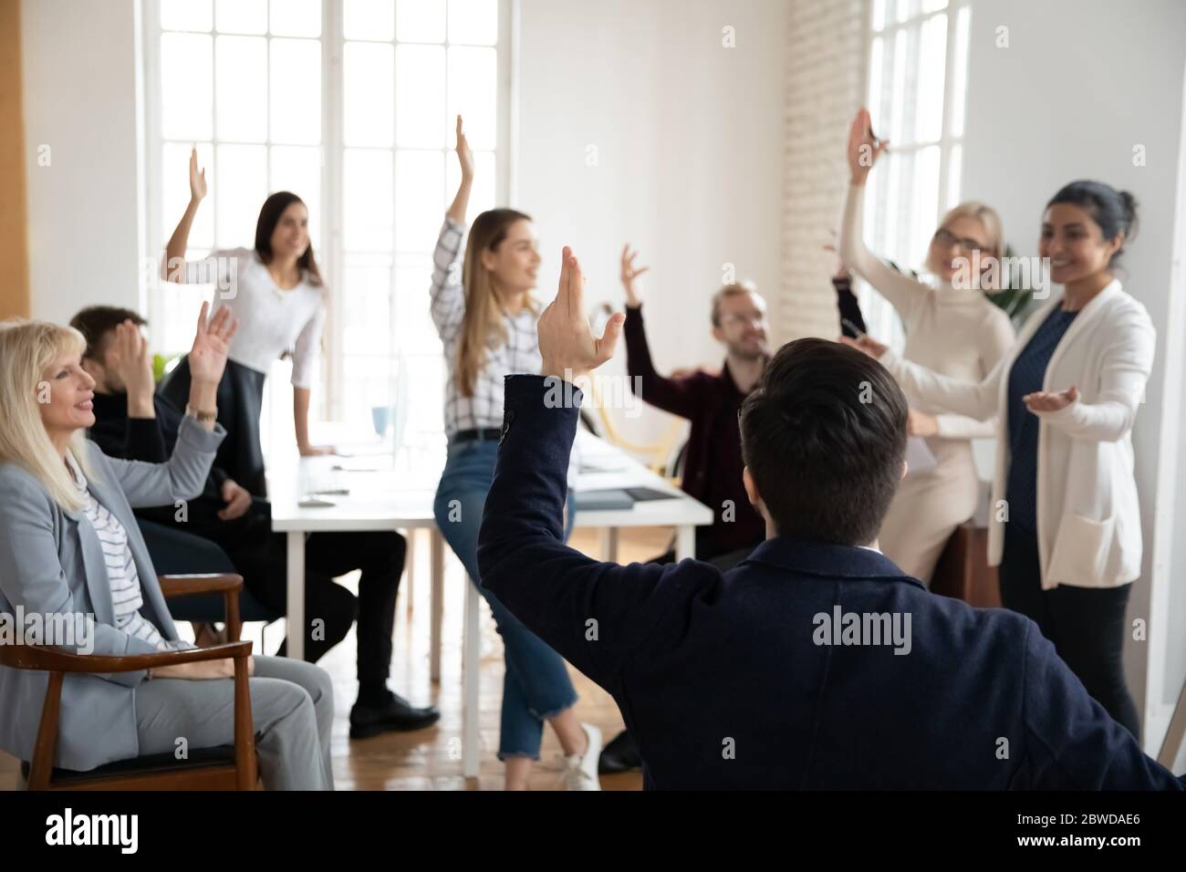 Happy different ages business people raising hands, having questions ...