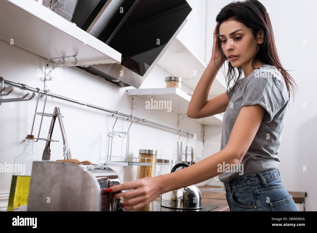 woman with bruise on face touching toaster in kitchen, domestic ...