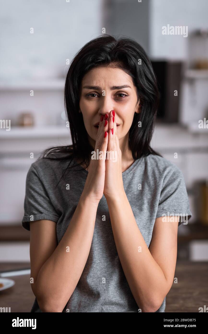 injured woman with bruise on face and praying hands, domestic violence ...