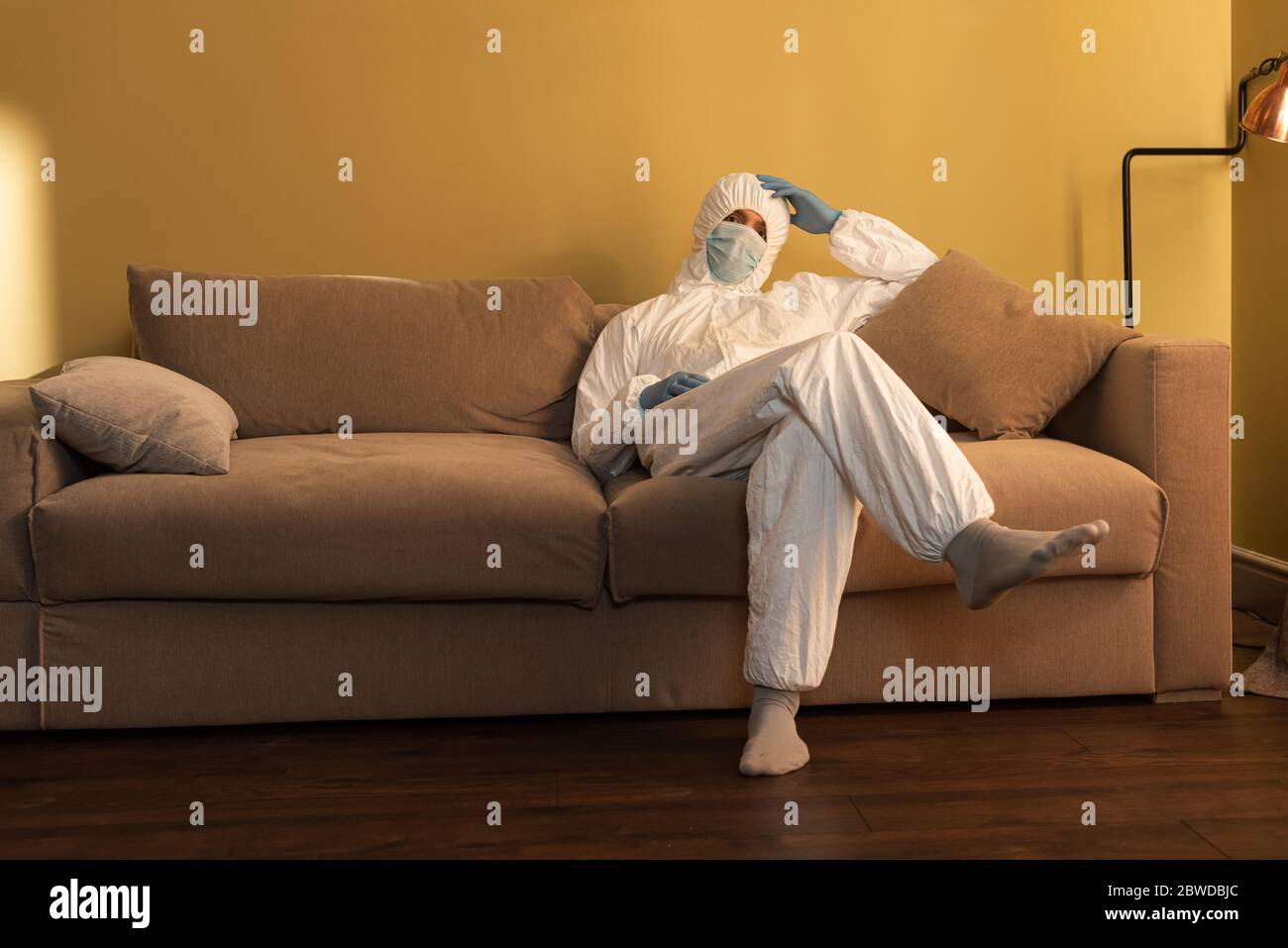 Man in medical mask, decontamination suit and latex gloves sitting on ...