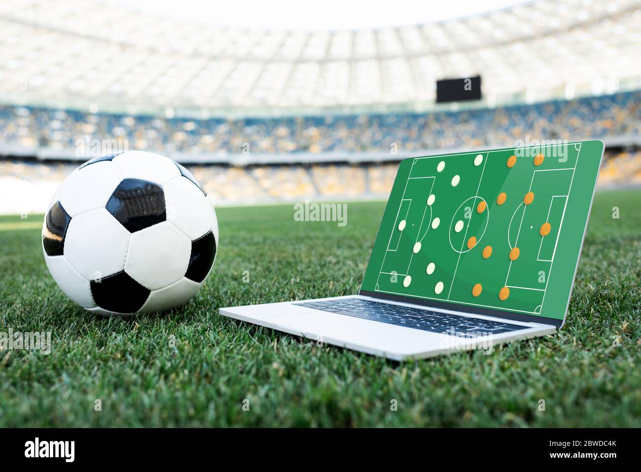 soccer ball and laptop with formation on screen on grassy football ...
