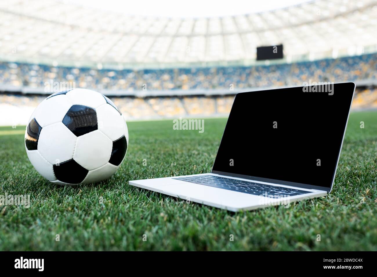 soccer ball and laptop with blank screen on grassy football pitch at ...