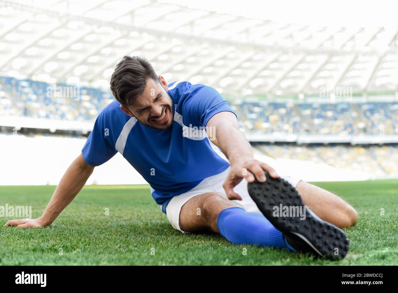 professional soccer player in blue and white uniform stretching on ...