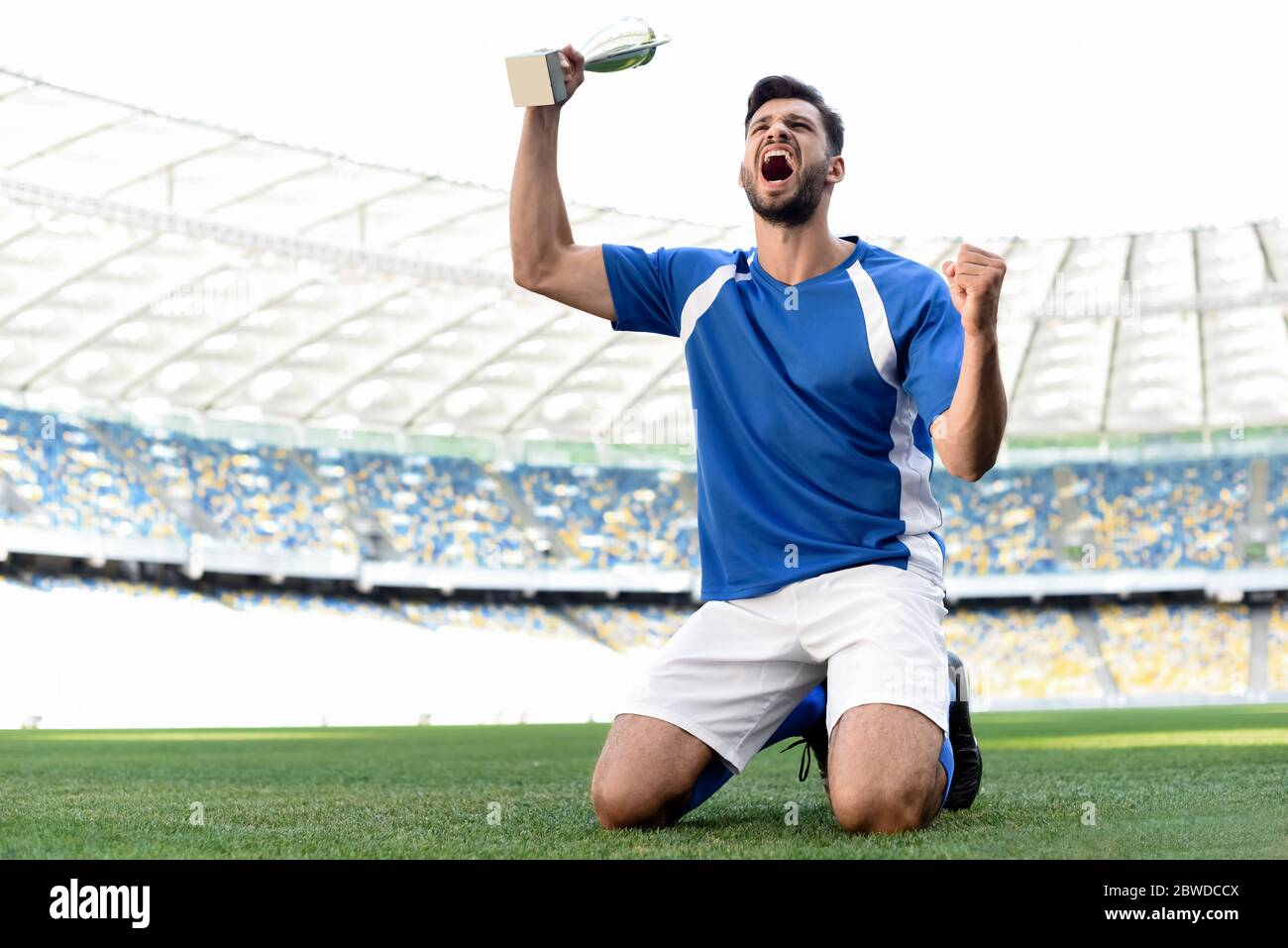 professional soccer player in blue and white uniform with sports cup ...